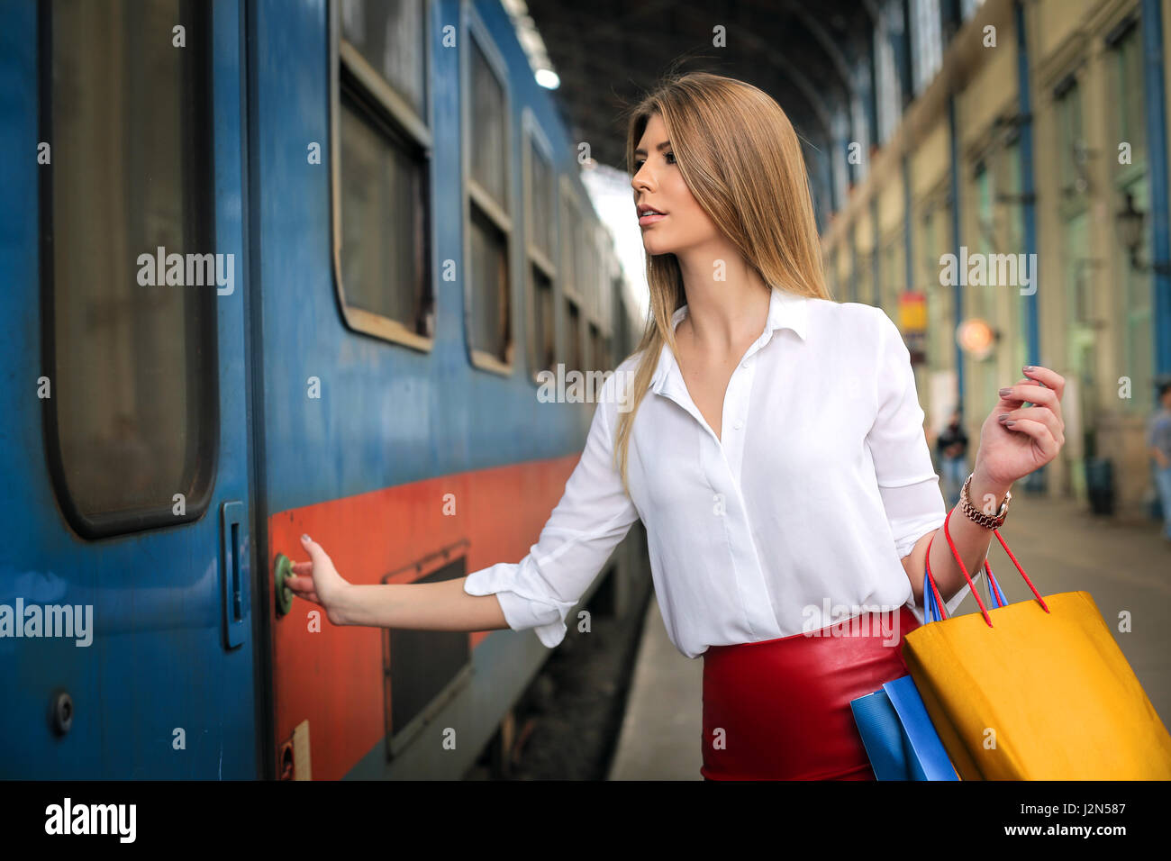 Young blonde woman getting on train Stock Photo - Alamy