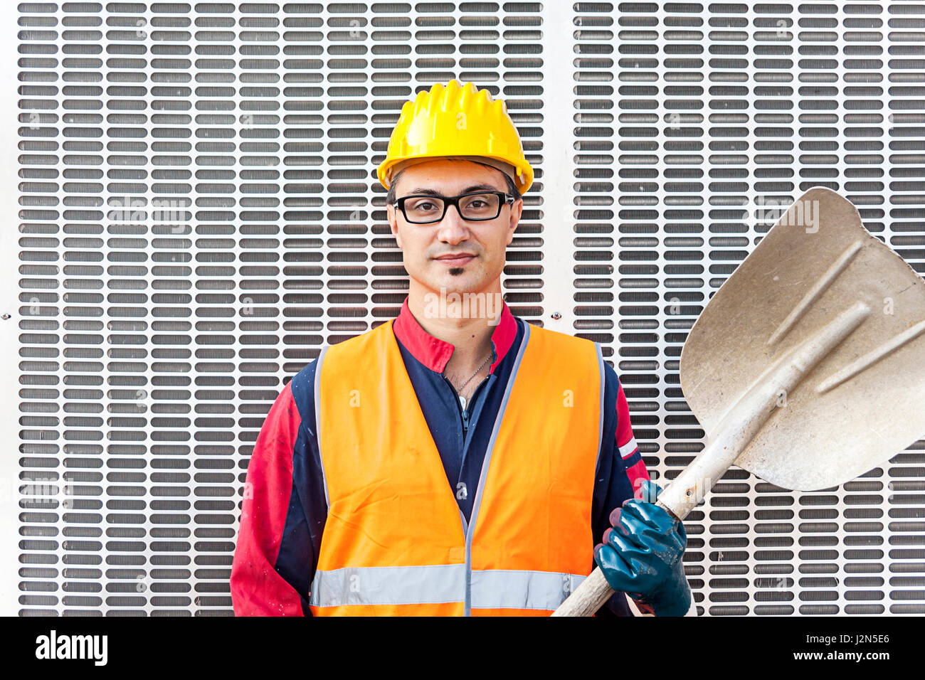 portrait of a young engineer wearing a helmet against metal background ...
