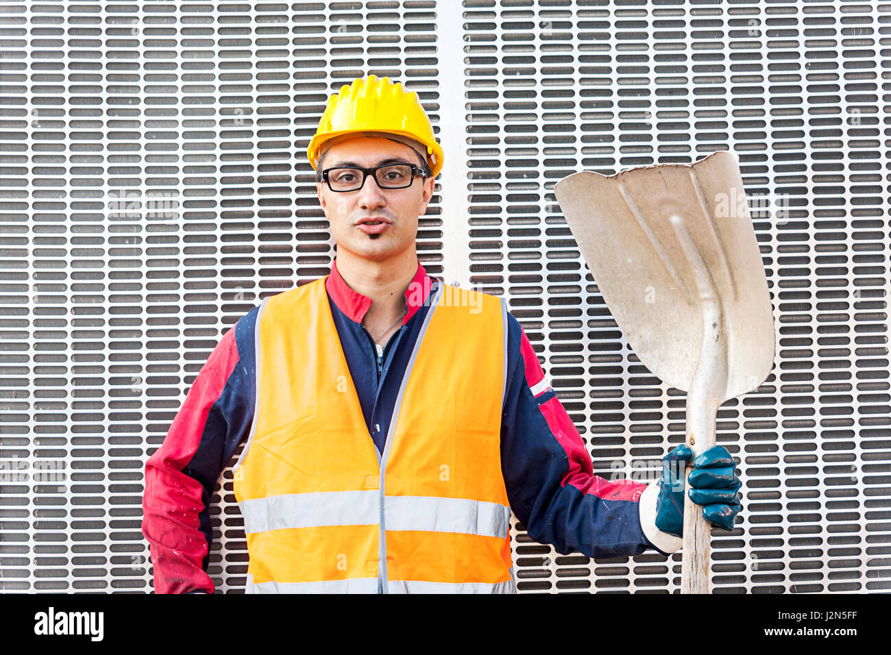 portrait of a young engineer wearing a helmet against metal background ...
