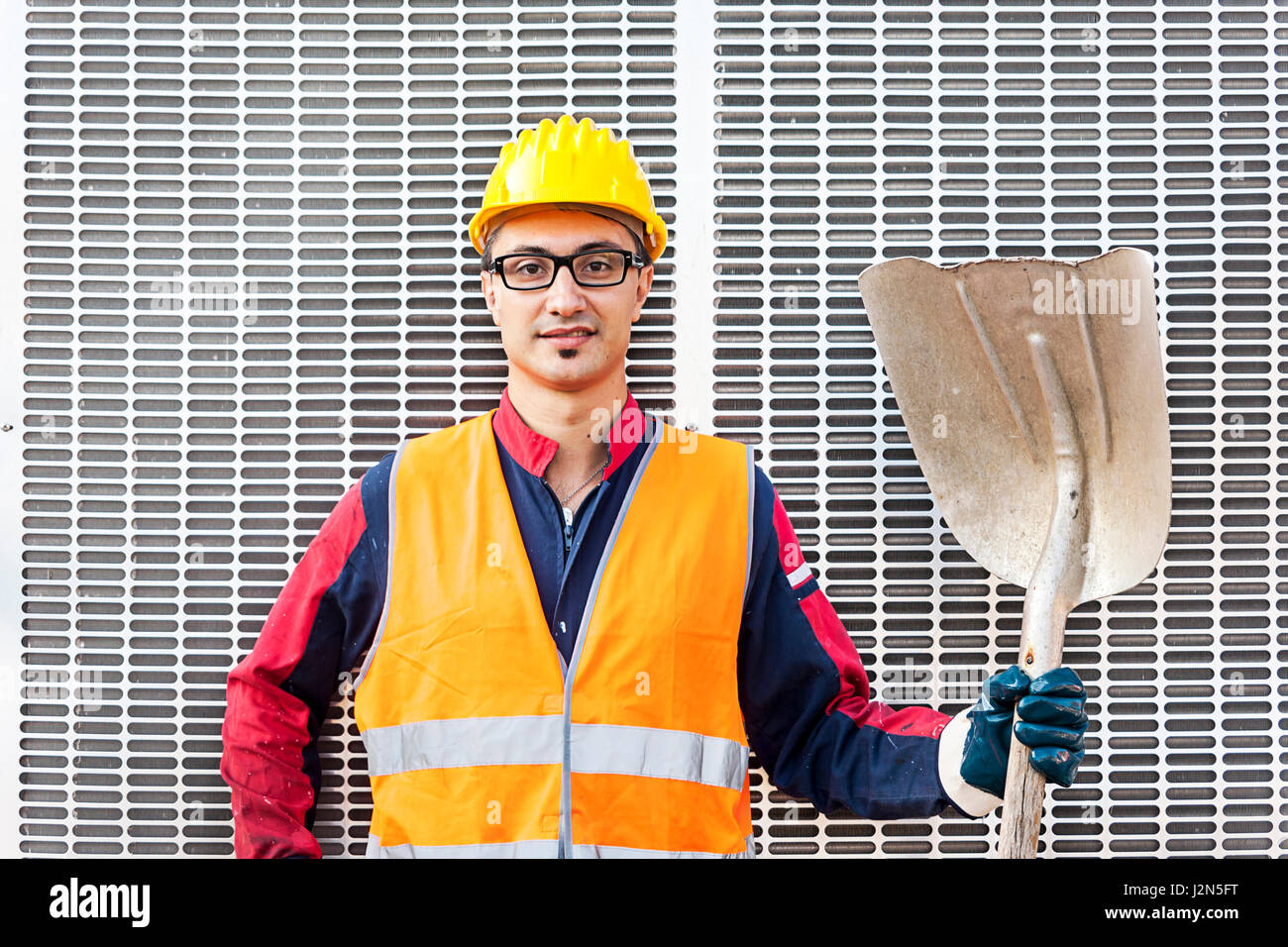 portrait of a young engineer wearing a helmet against metal background ...