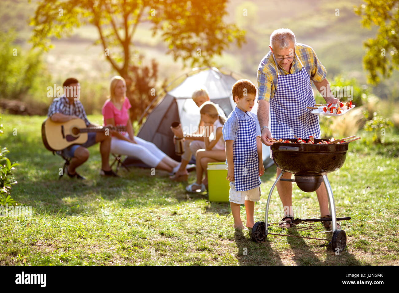 happy family camping and making barbecue Stock Photo - Alamy