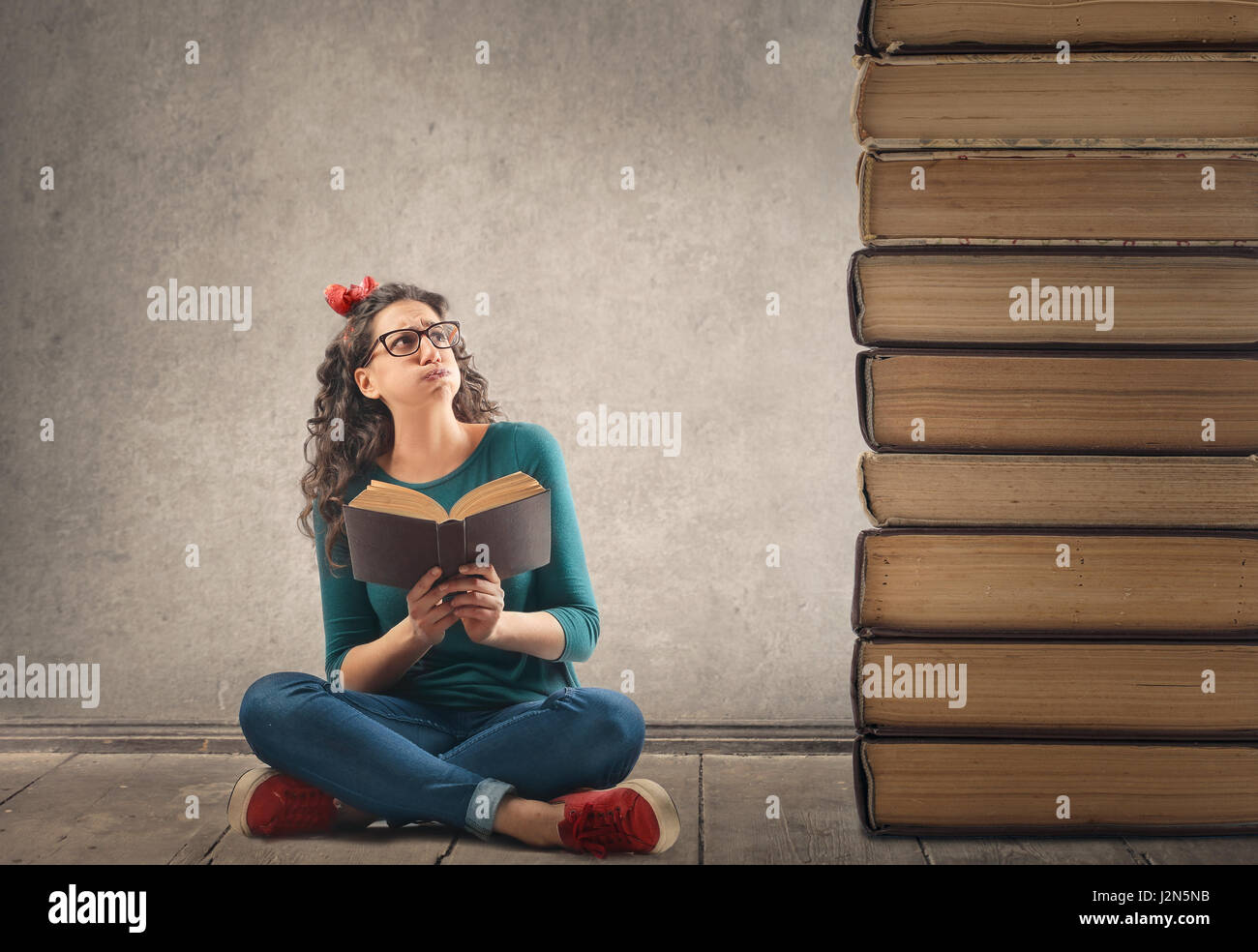 Woman reading next to huge books Stock Photo - Alamy