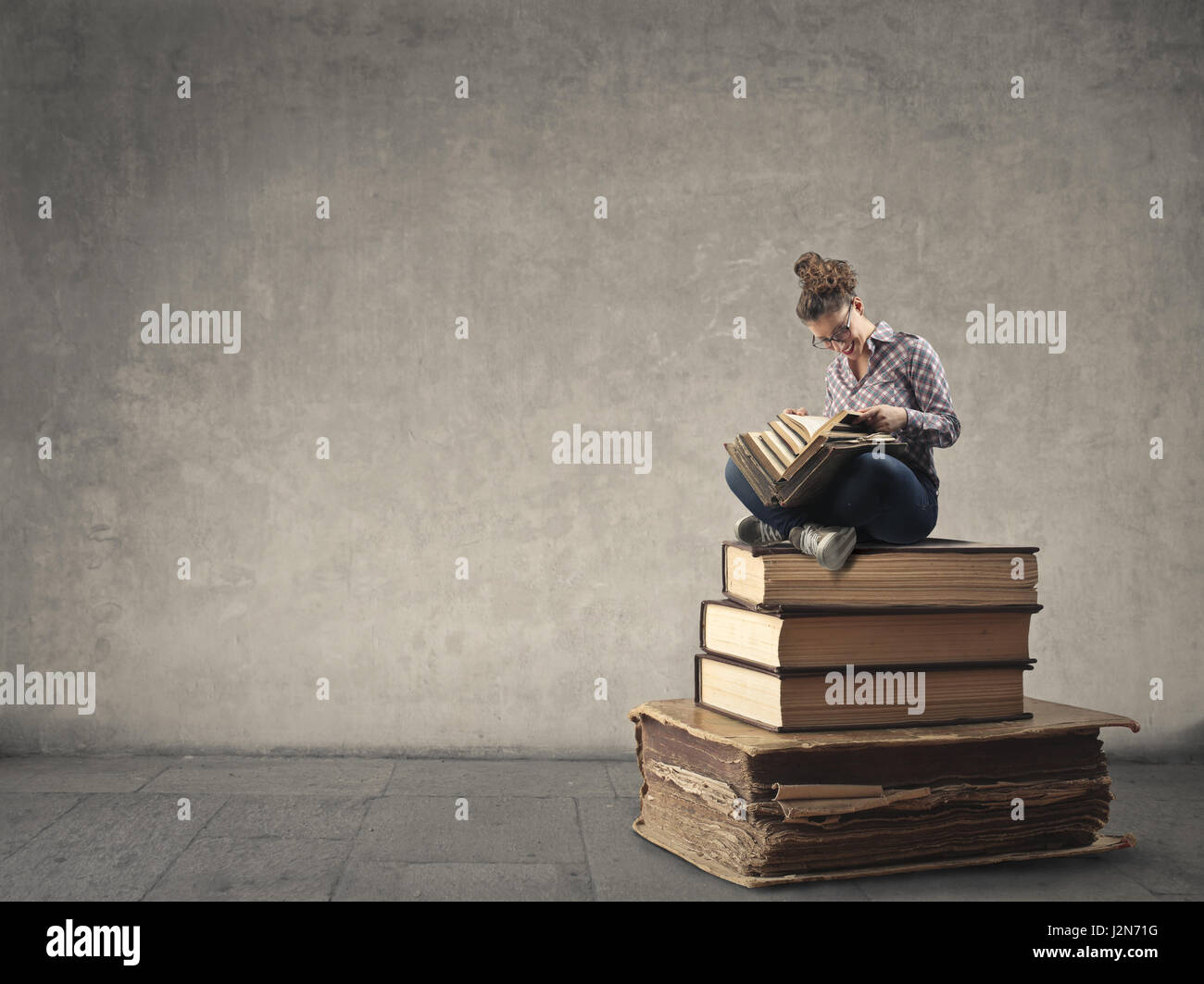 Woman sitting on books Stock Photo - Alamy