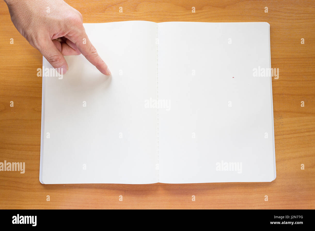 Four hands with finger pointing at blank white paper notebook on wood ...