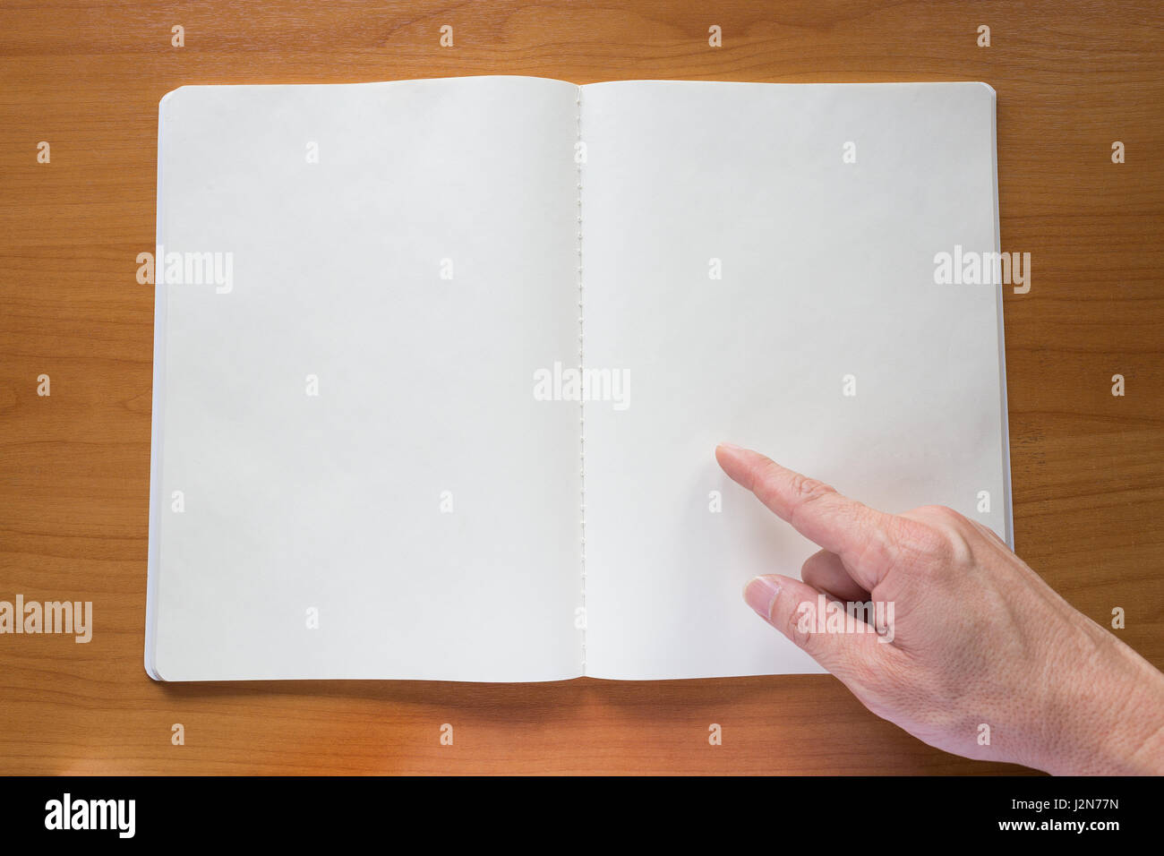 single hands with finger pointing at blank white paper notebook, lower ...