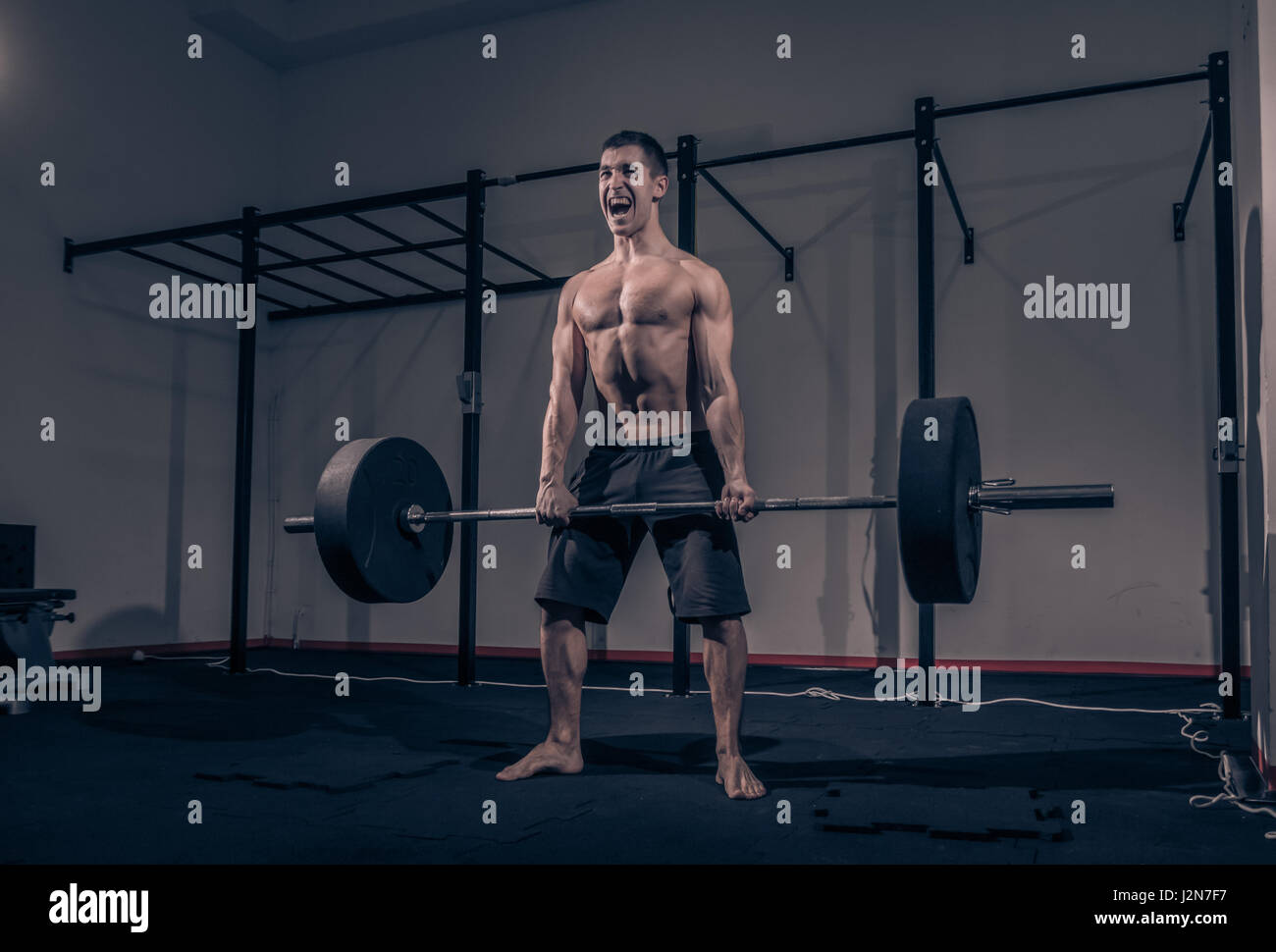 one young adult man bodybuilder, shouting screaming deadlift barbell ...