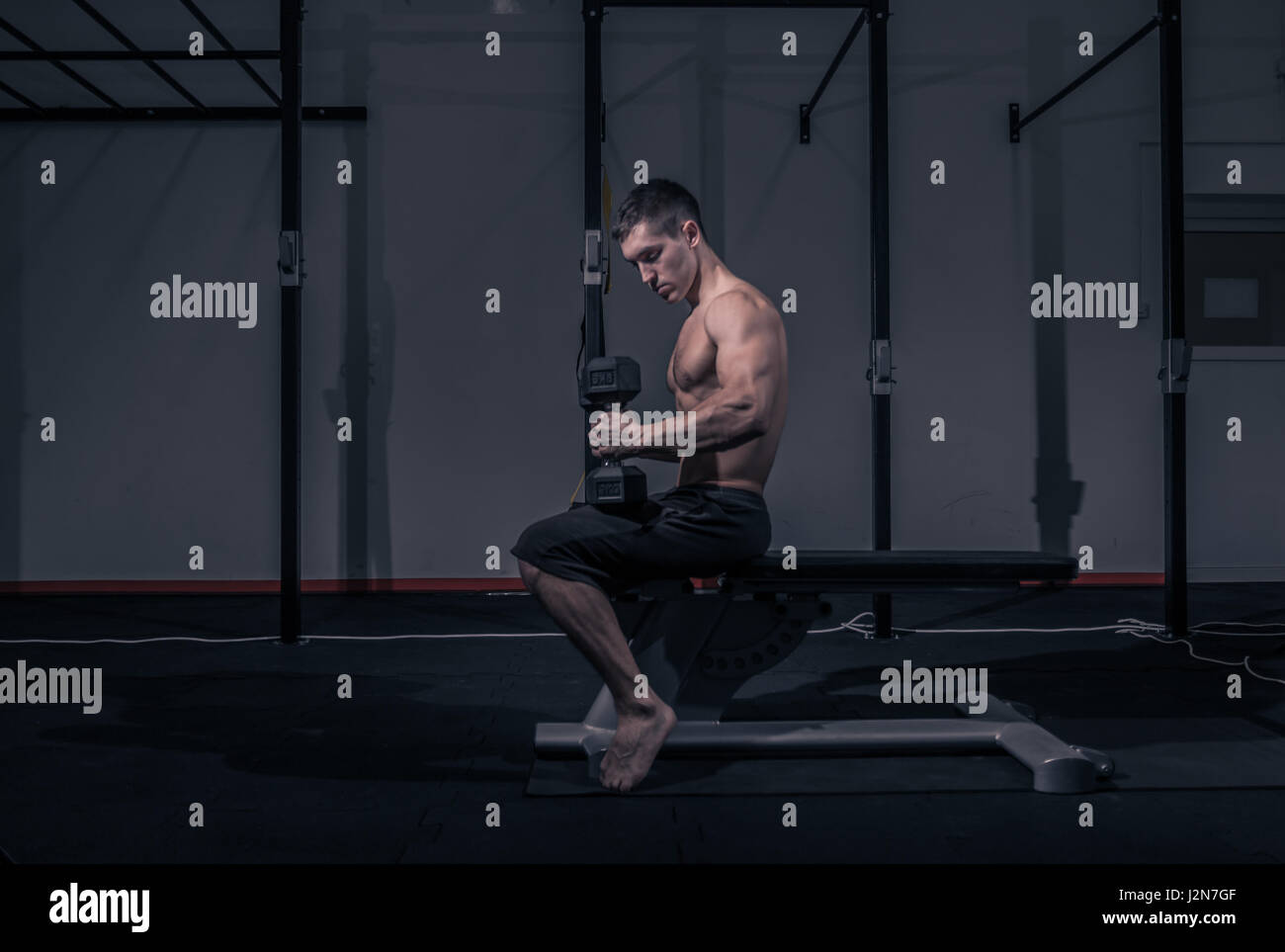 one young man, bodybuilder sitting, flat bench, dumbbell posing ...