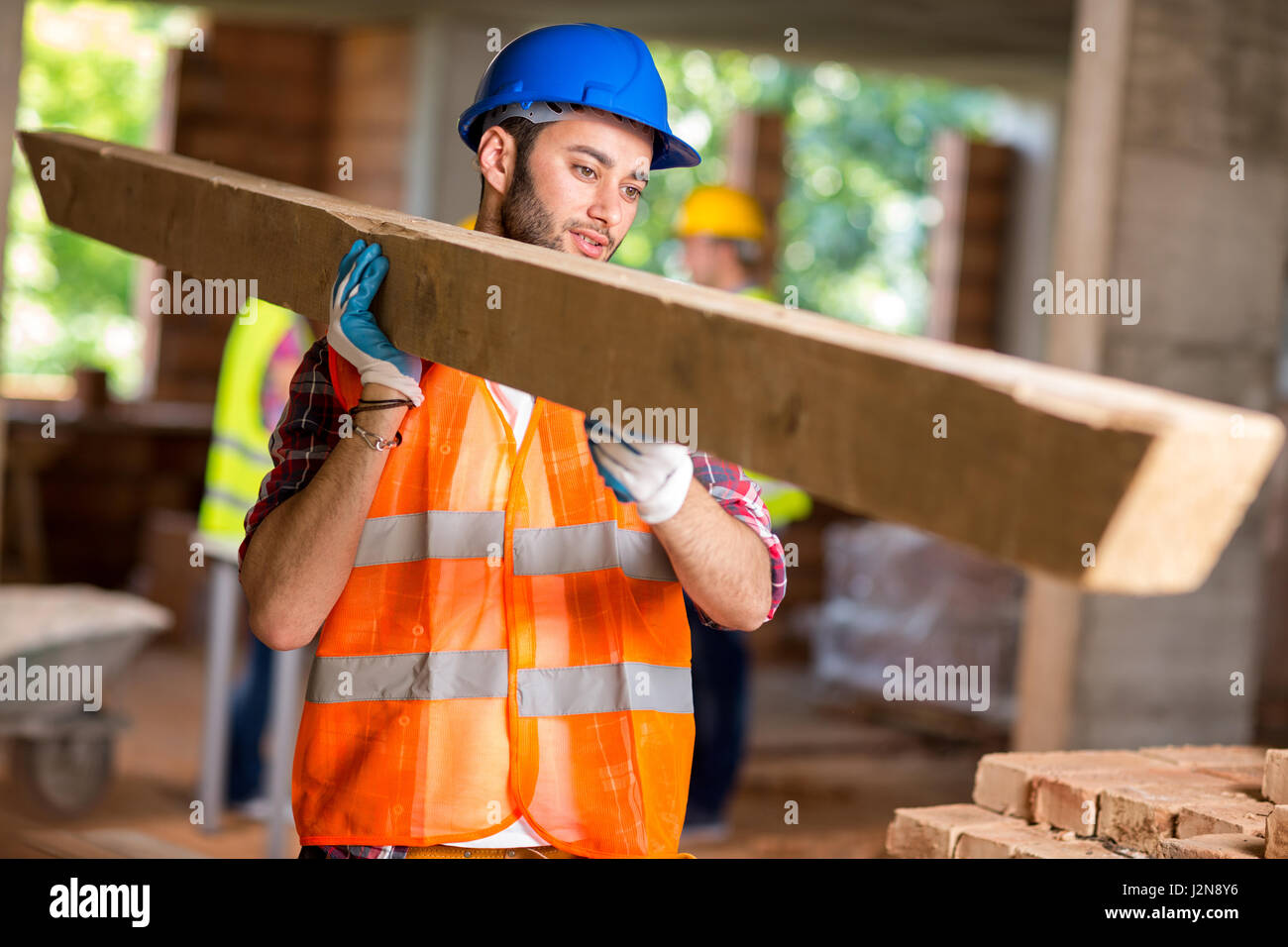 Young worker bring construction timber at work Stock Photo - Alamy