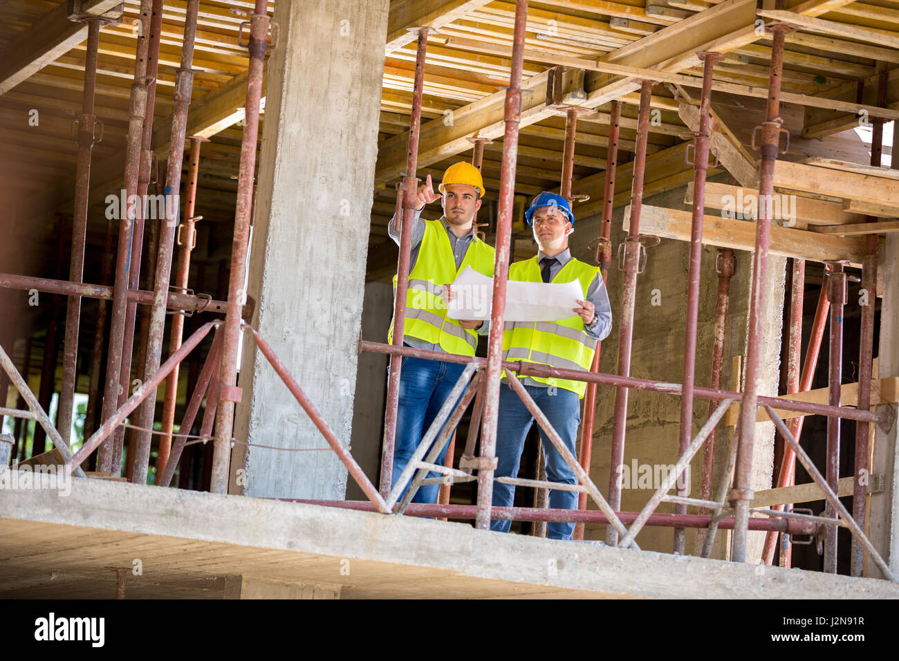 Architect and worker in building construction monitoring work Stock ...