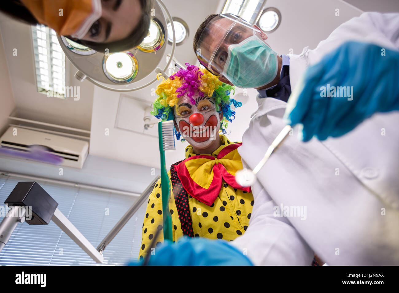 Clown with dentist holding toothbrush in dental clinic, bottom view ...