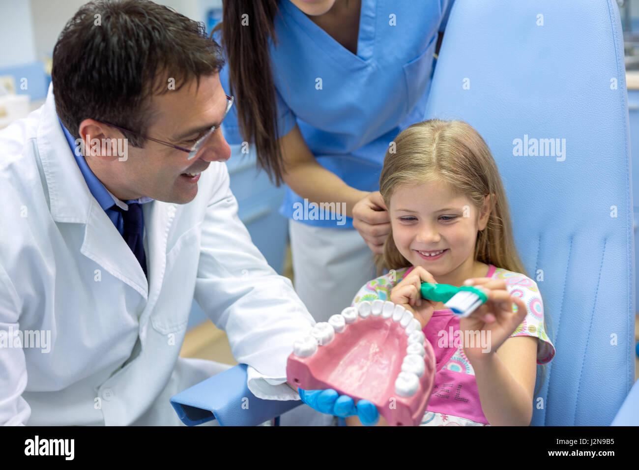 Girl with big toothbrush learn hoe to properly brush teeth on model of ...