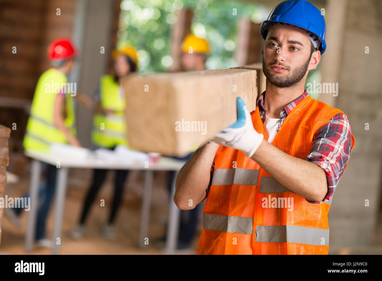Young worker bring construction beam at work Stock Photo - Alamy
