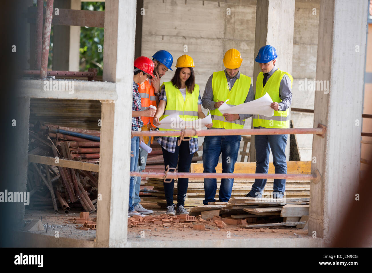 Team of young architecture experts studying blue print at open air ...