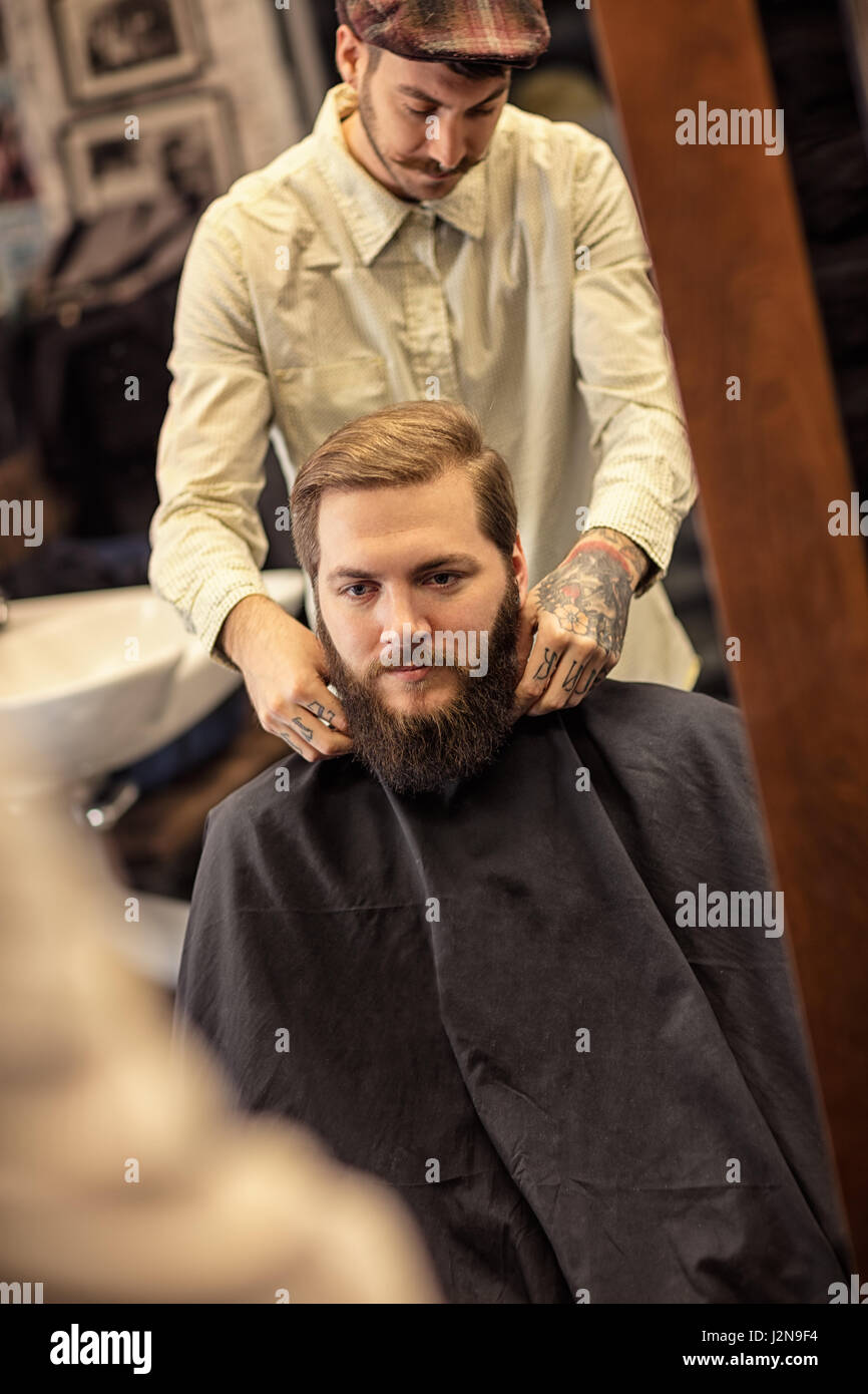 Barber tying apron around customer for grooming Stock Photo - Alamy