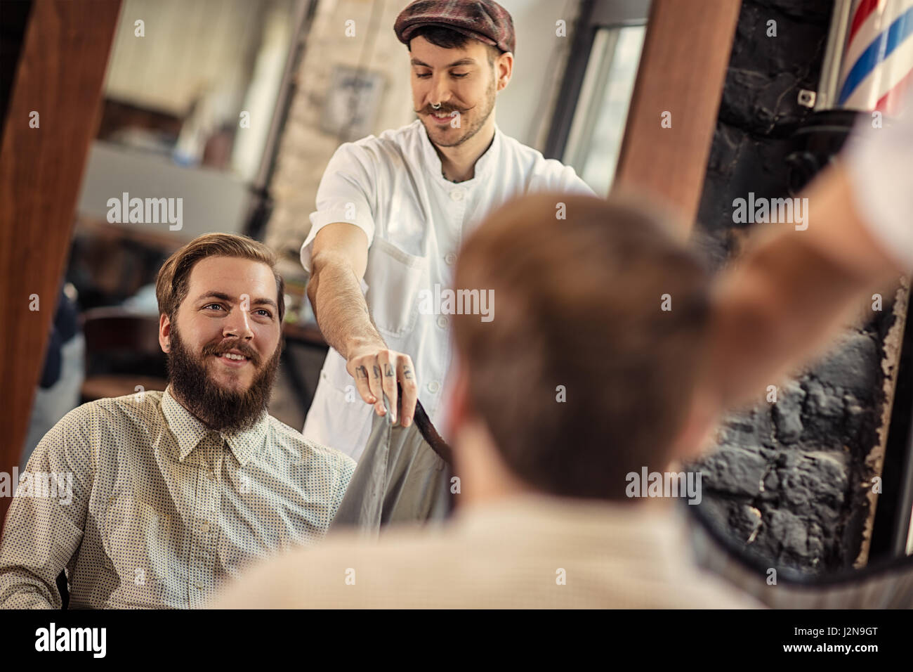 Smiling client is sitting in barber shop front of the mirrors Stock ...