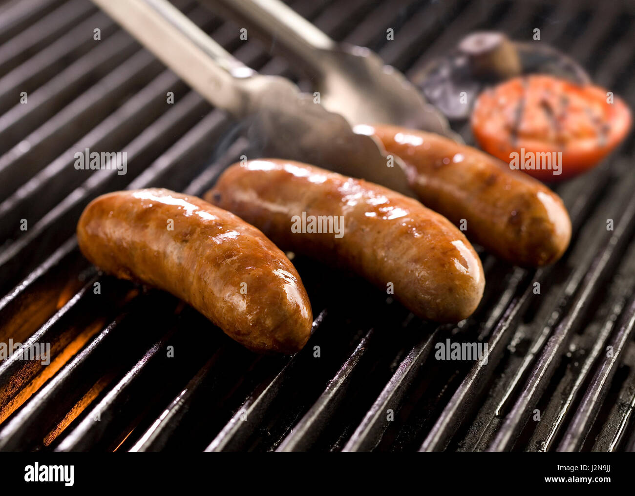 Sausages cooking on a grill Stock Photo - Alamy