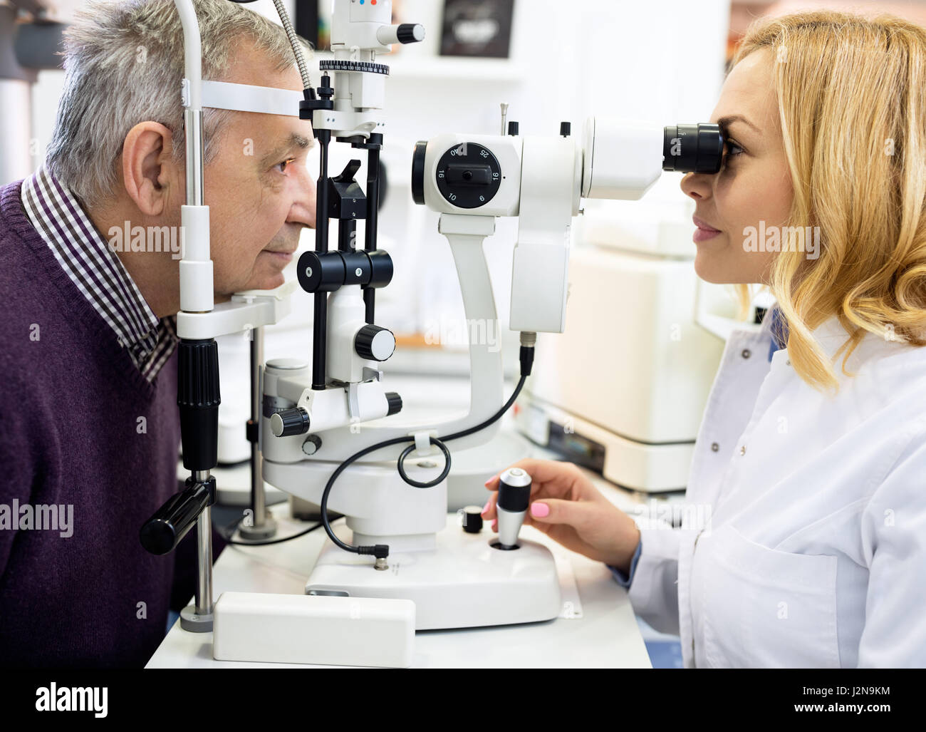 Female ophthalmic doctor check eyes to elderly man in eye clinic Stock ...