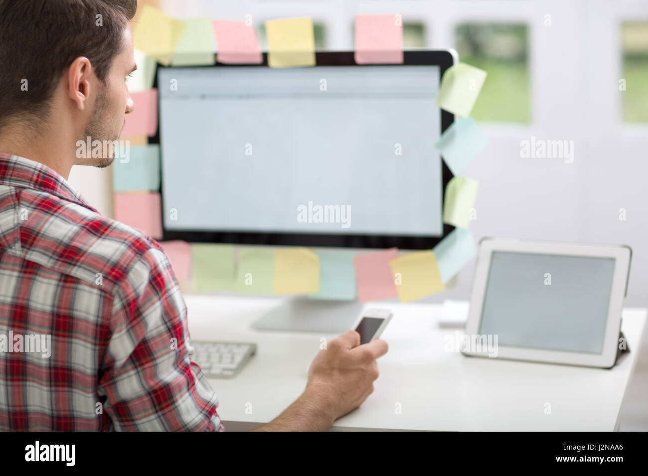 Man at modern office looking at monitor with sticky note Stock Photo ...
