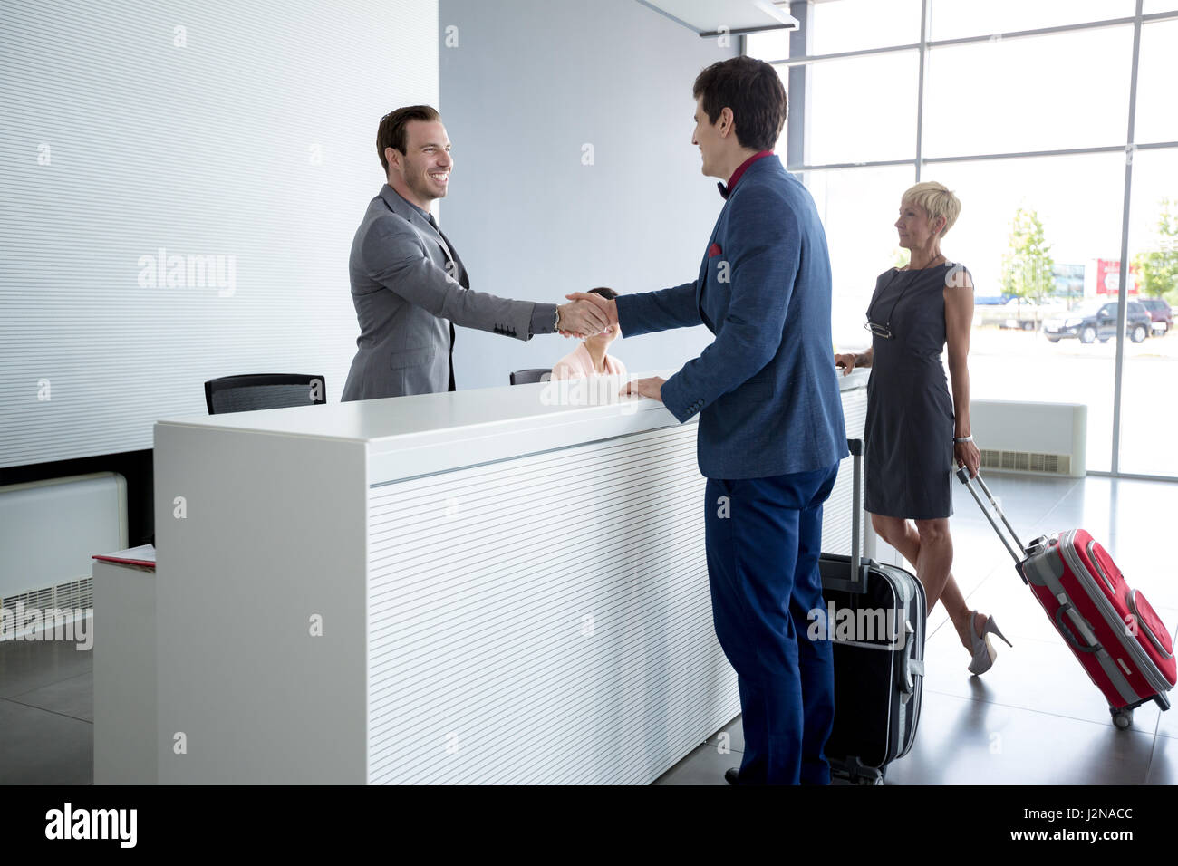 Man and receptionist handshake at reception hall Stock Photo - Alamy