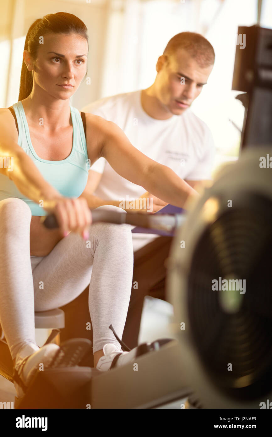 Gym woman with supervision of a personal trainer doing exercise at the ...
