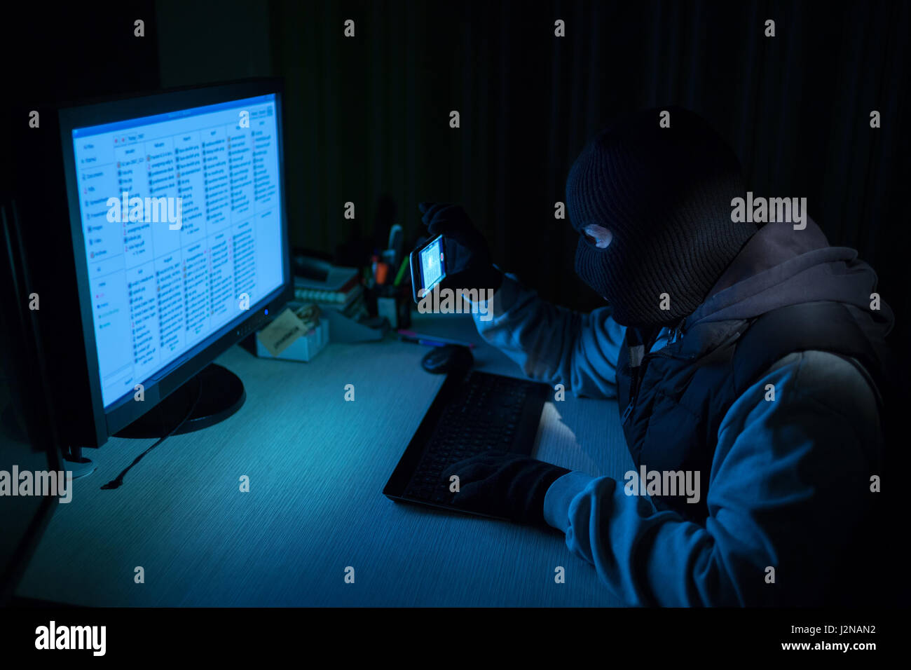 Computer hacker with smart phone make photo and data on it Stock Photo ...