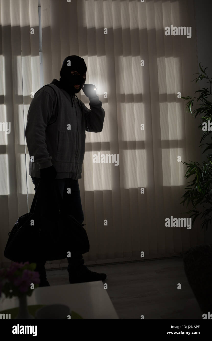 Robber in a mask with flashlight Stock Photo - Alamy