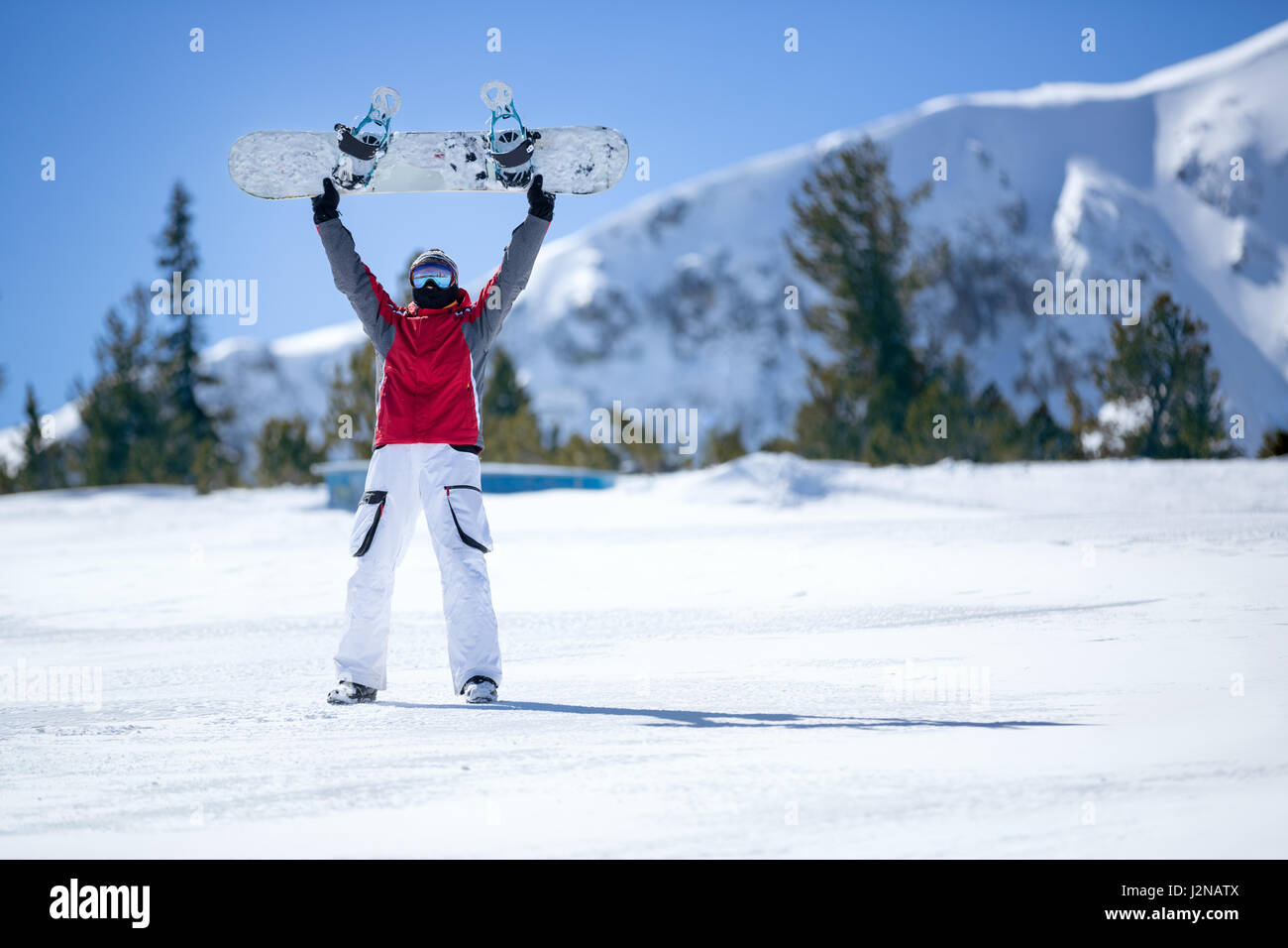 Happy snowboarder holding snowboard over head Stock Photo - Alamy