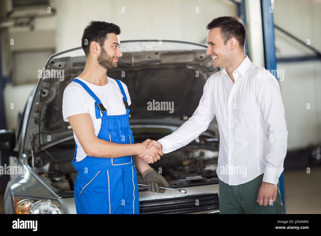 Smiling client and mechanic shaking hands in sevice Stock Photo - Alamy