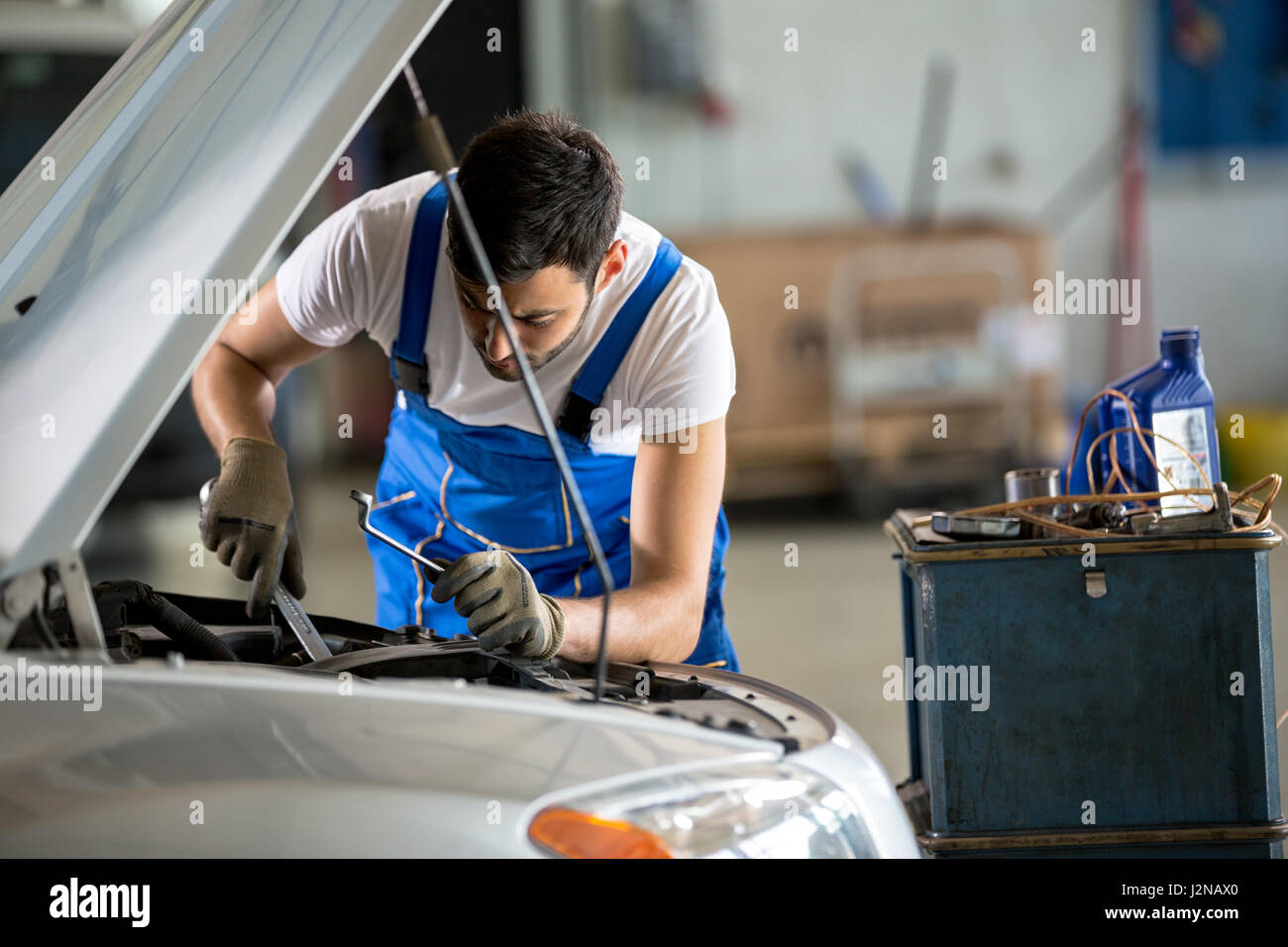 Auto mechanic working under the hood in garage Stock Photo - Alamy
