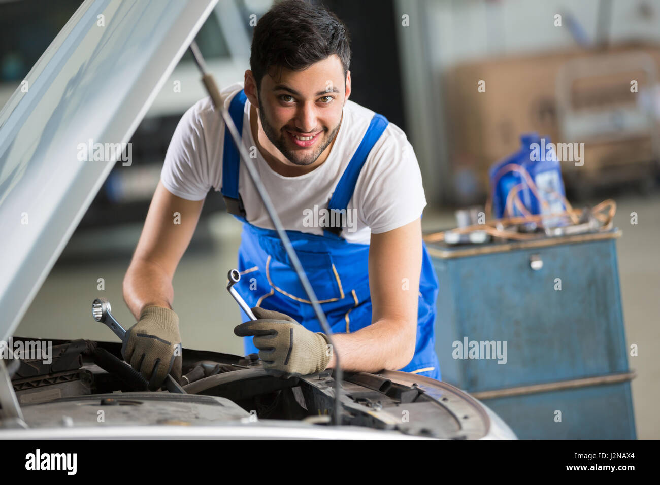 smiling mechanic working on engine in garage Stock Photo - Alamy