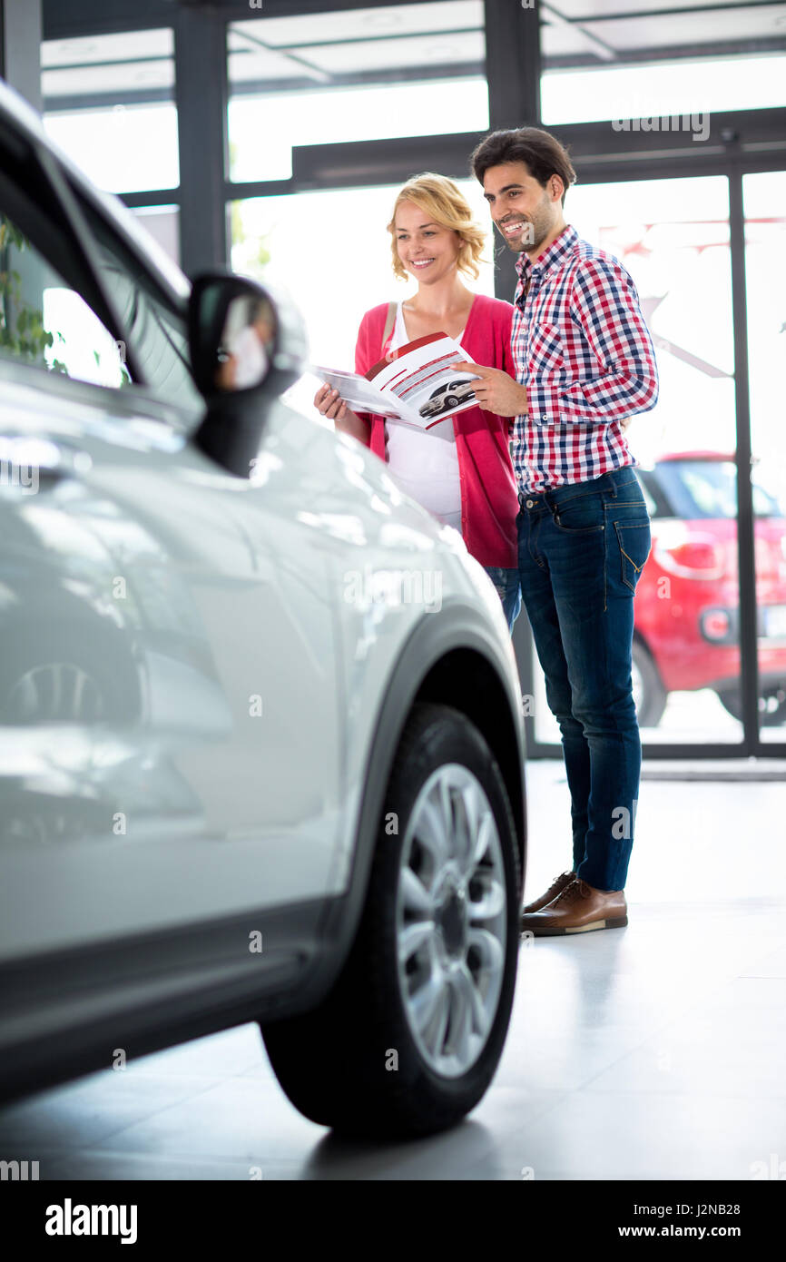 Happy couple standing front of his favorite model of car in car ...