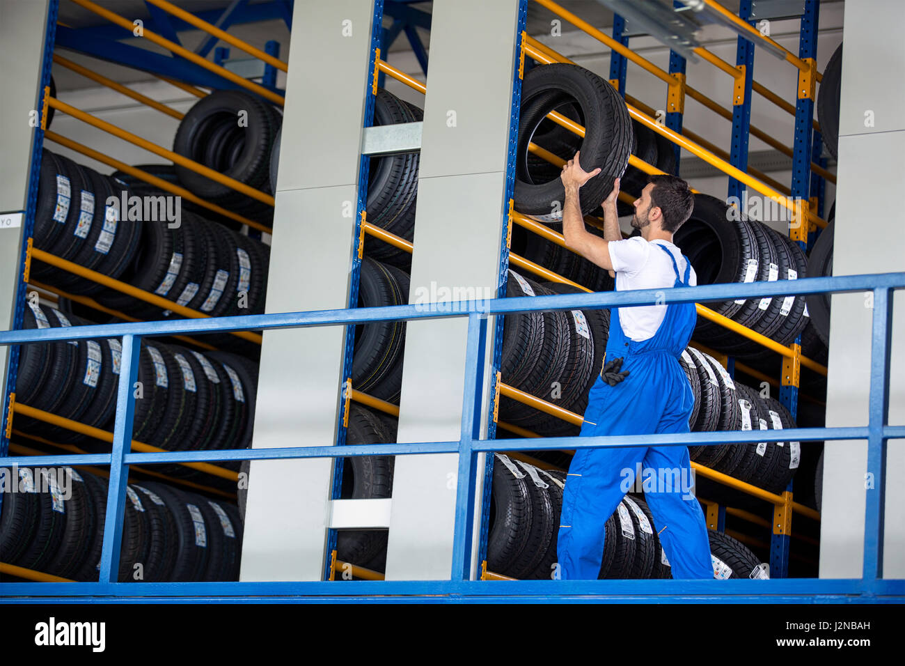 Auto Auto mechanic pushes the car tire in tire store Stock Photo - Alamy