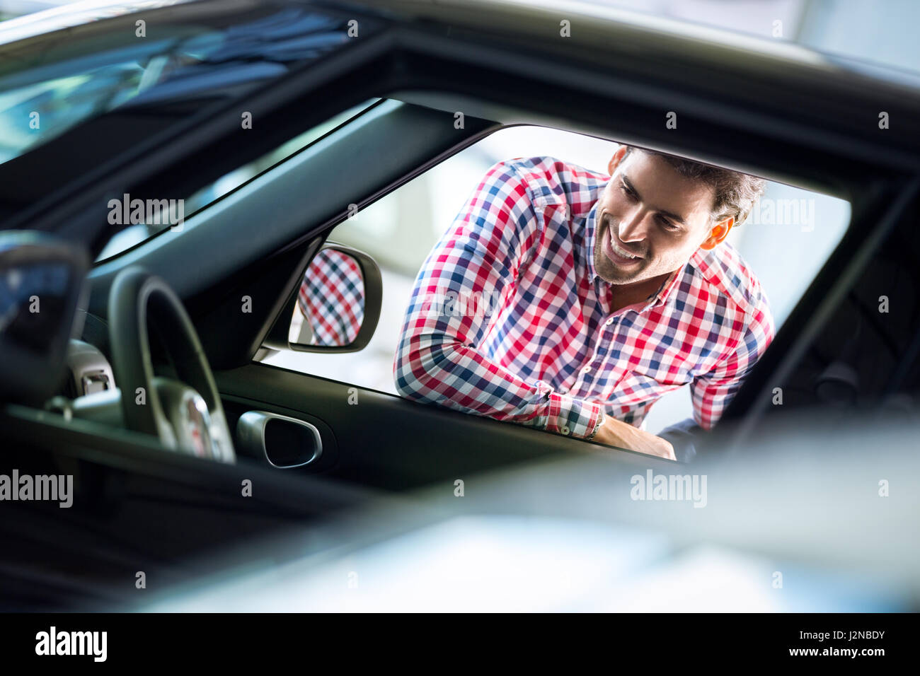 smiling young man looking in interior of a new car Stock Photo - Alamy