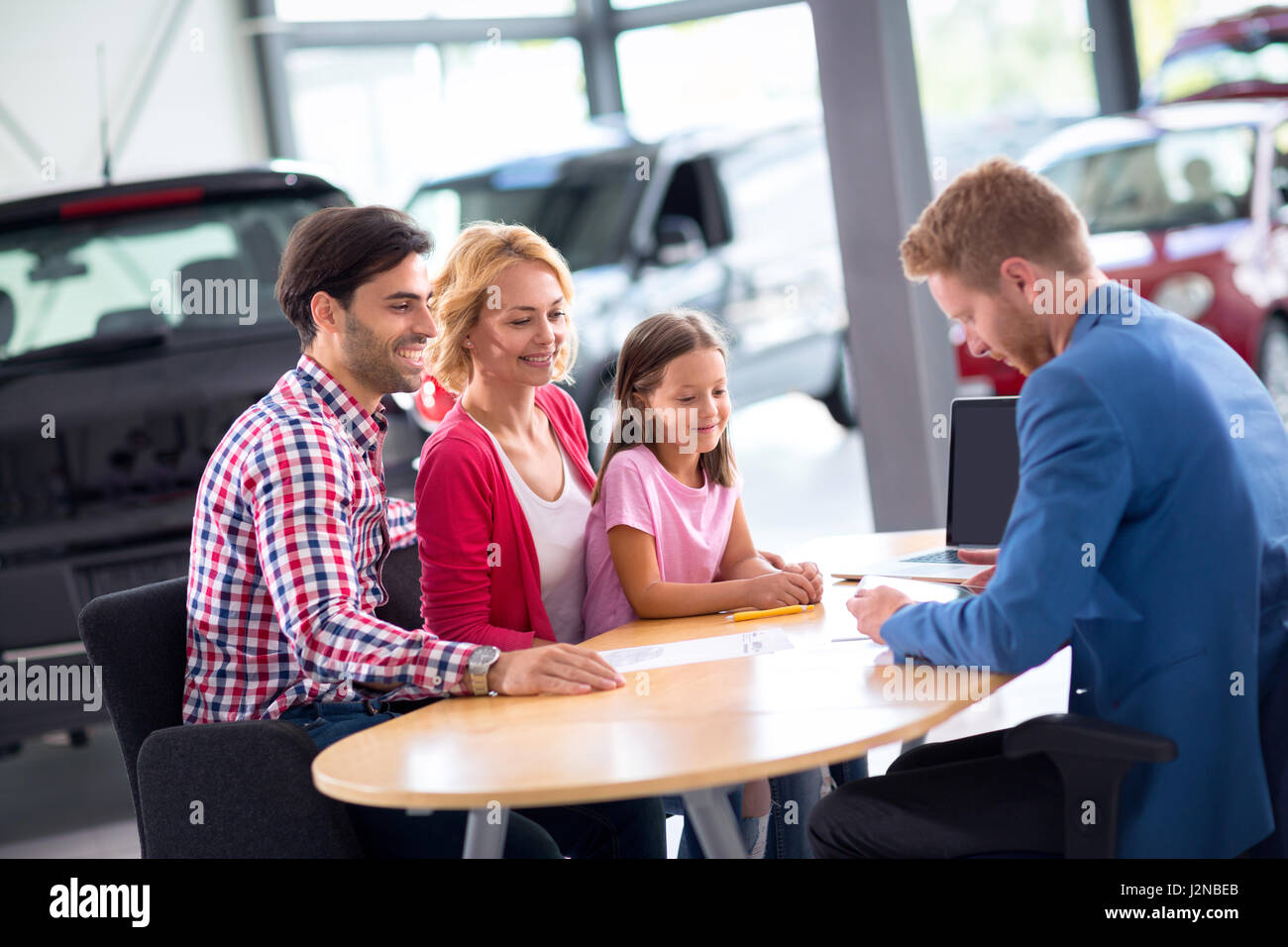 car agent demonstrating new automobile to young family with child Stock ...