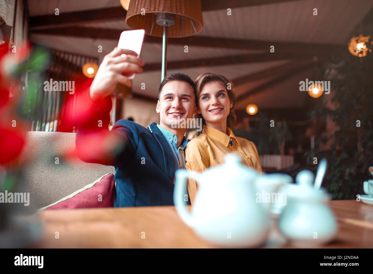 Love couple hugs and makes selfie on phone camera in restaurant. Man ...