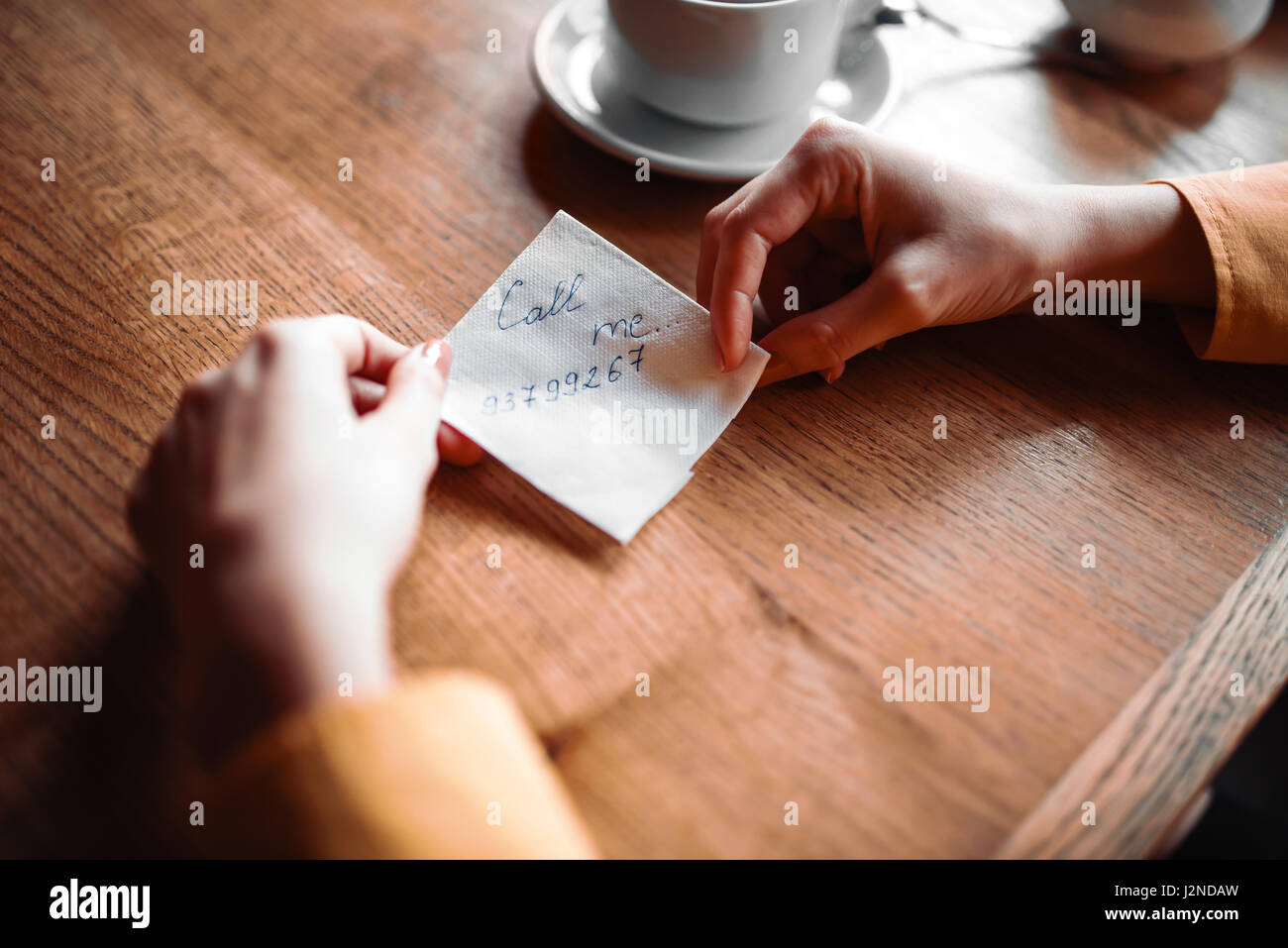 Female person hands holds love note with a phone number closeup view ...