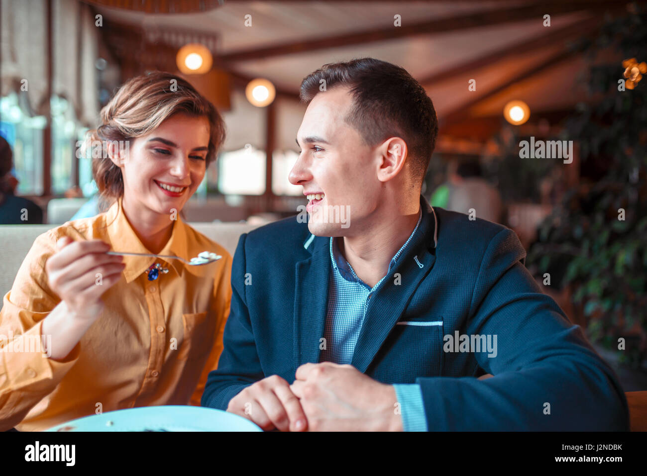 Young woman feeding man with a spoon in restaurant. Love cople at ...