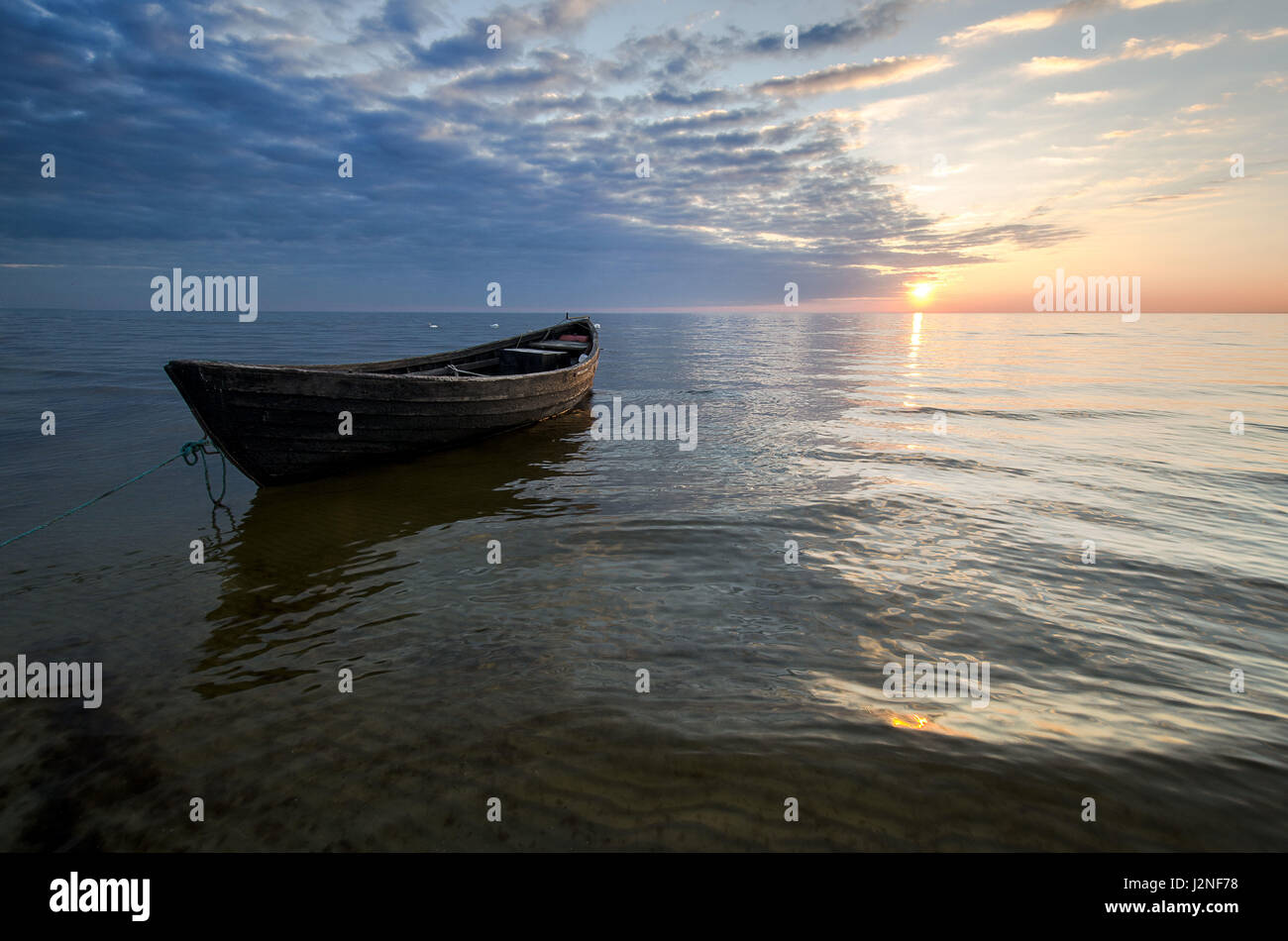 Lonely boat on the sea at sunset Stock Photo - Alamy