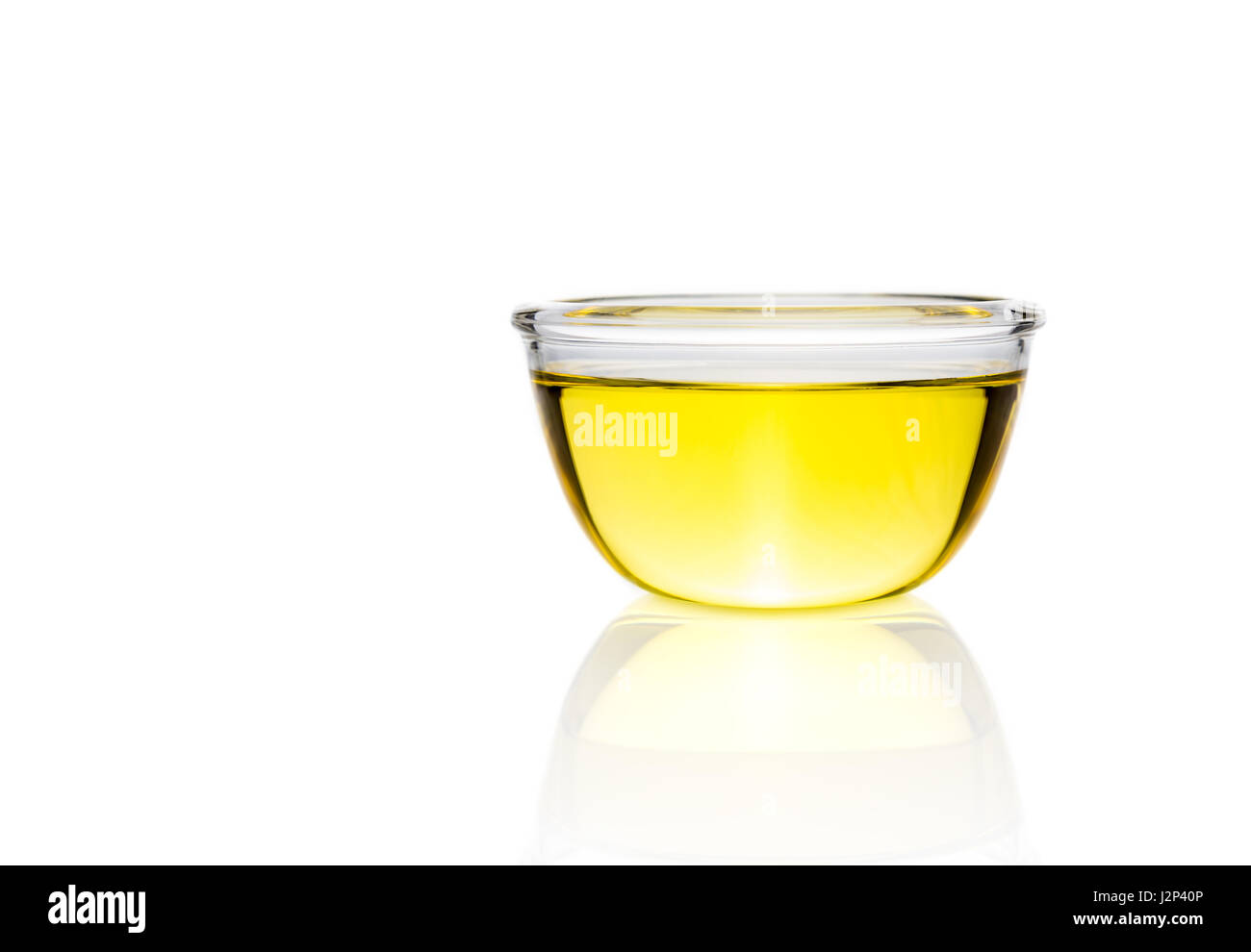 Yellow liquid, oil, in clear glass bowl on white background with light ...