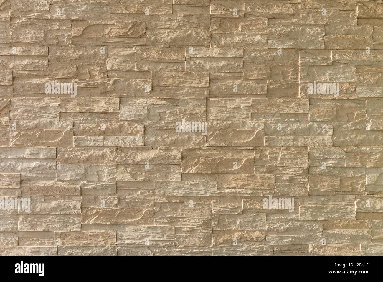 light brown stone brick exterior wall in hard light emphasizing stone's ...