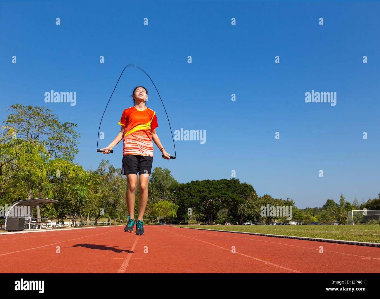 young female asian athlete rope jumping outdoor on running track at ...