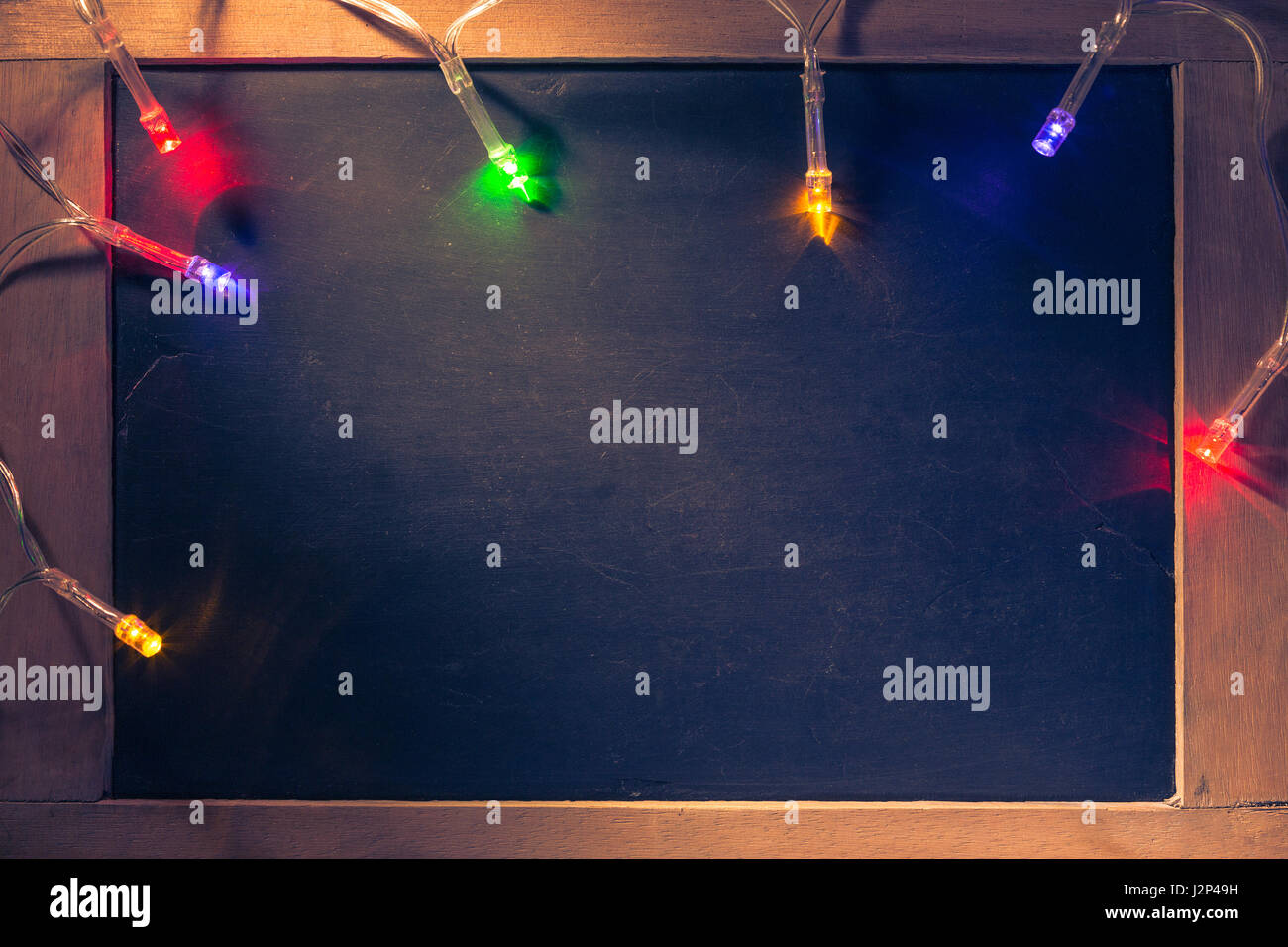 Strip of colorful Christmas lights on top of small blackboard with beam ...