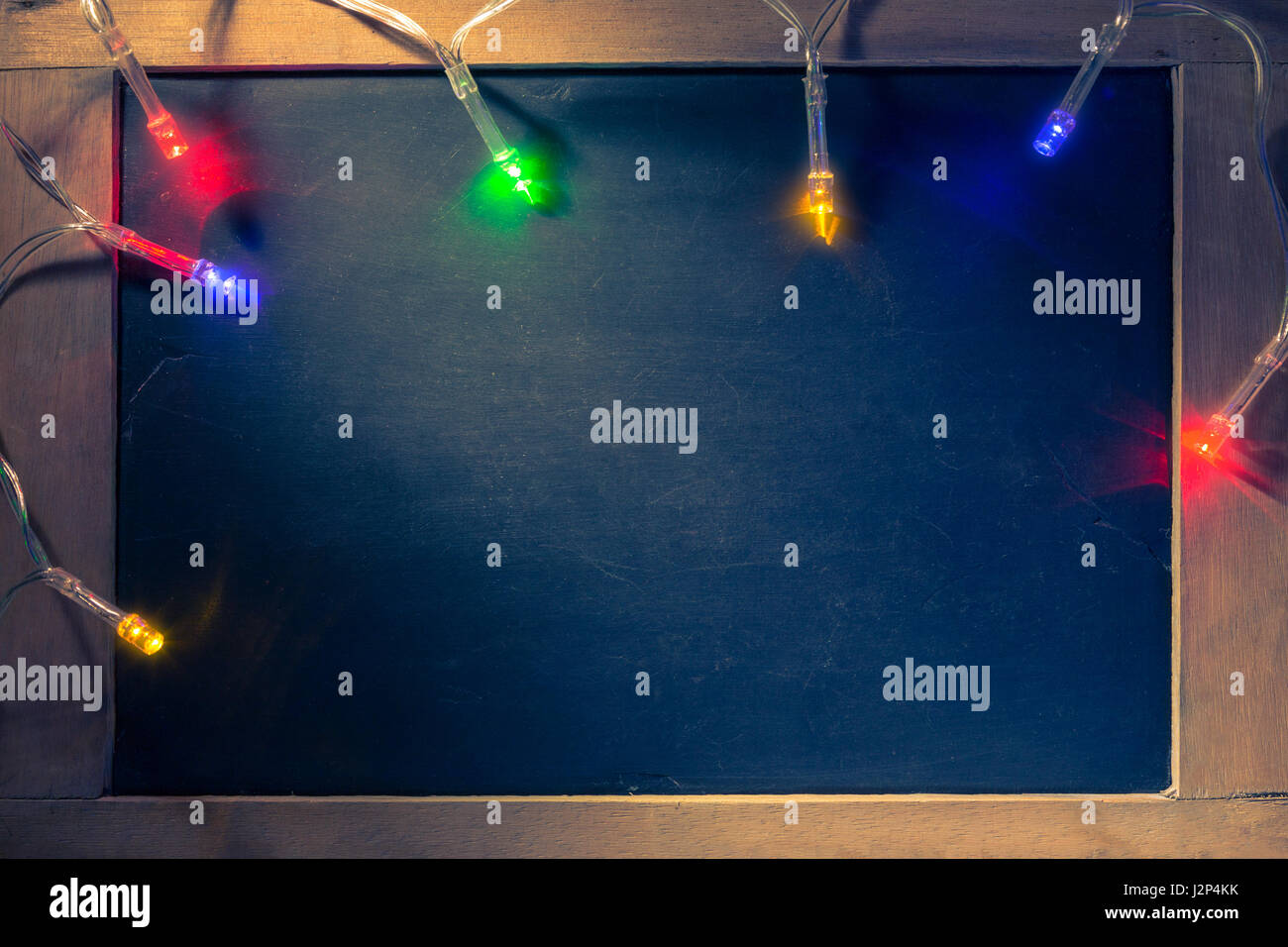 Strip of colorful Christmas lights on top of small blackboard with beam ...