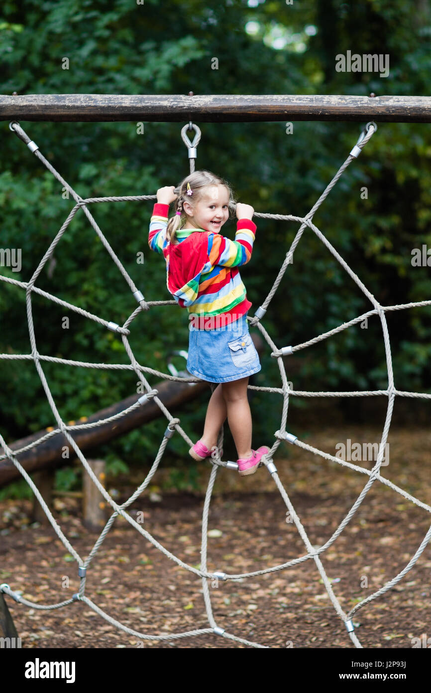 Active little child playing on climbing net and jumping on trampoline ...