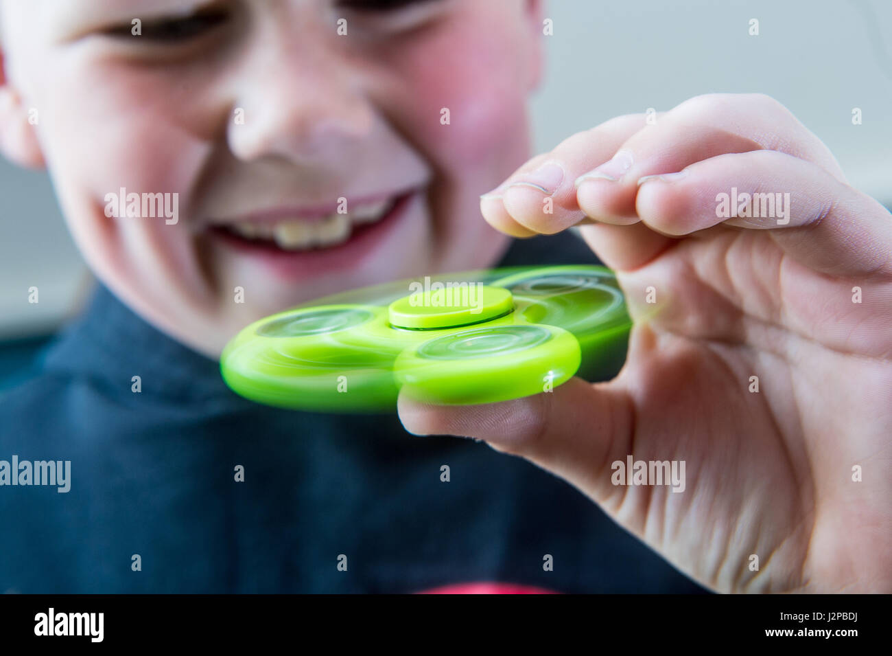 A young boy splays with a green fidget spinner Stock Photo - Alamy
