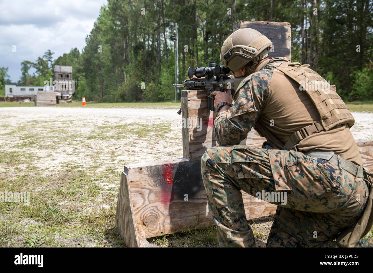 A Marine uses a barricade to stabilize his rifle during an urban sniper ...