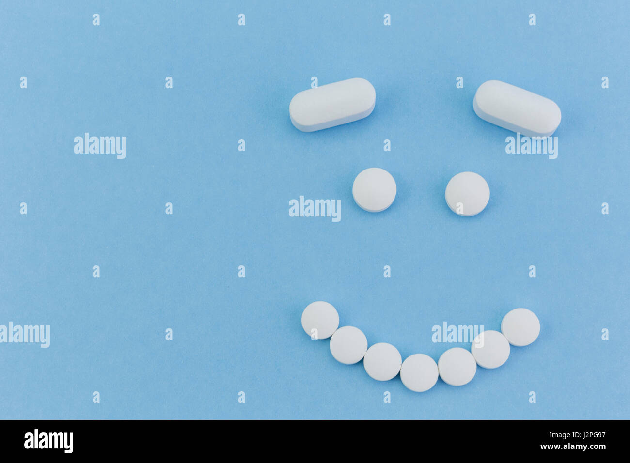 upset face made by pills on blue background Stock Photo - Alamy