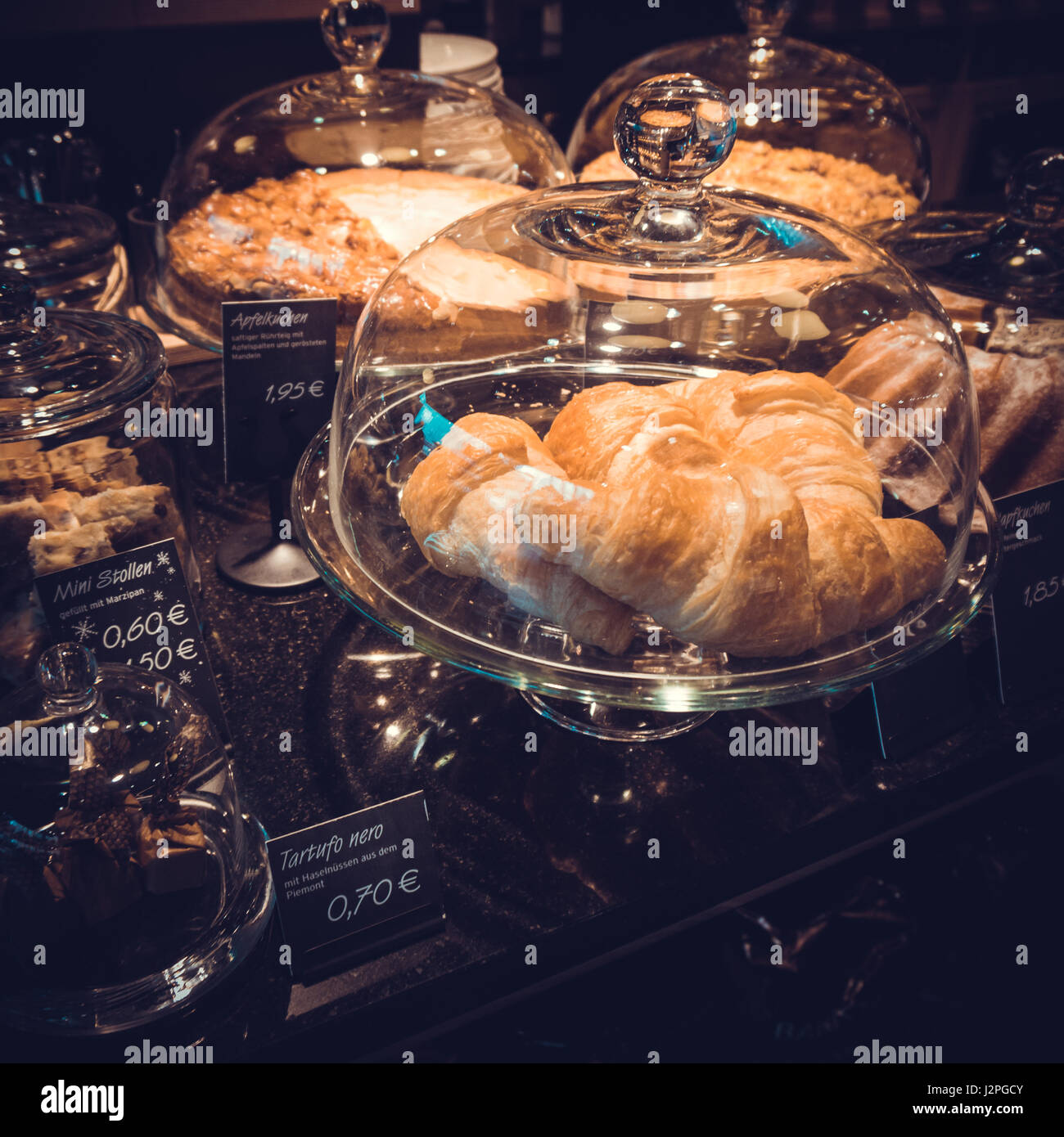 Cakes under bell-glass on display. bakery glass case full of different ...