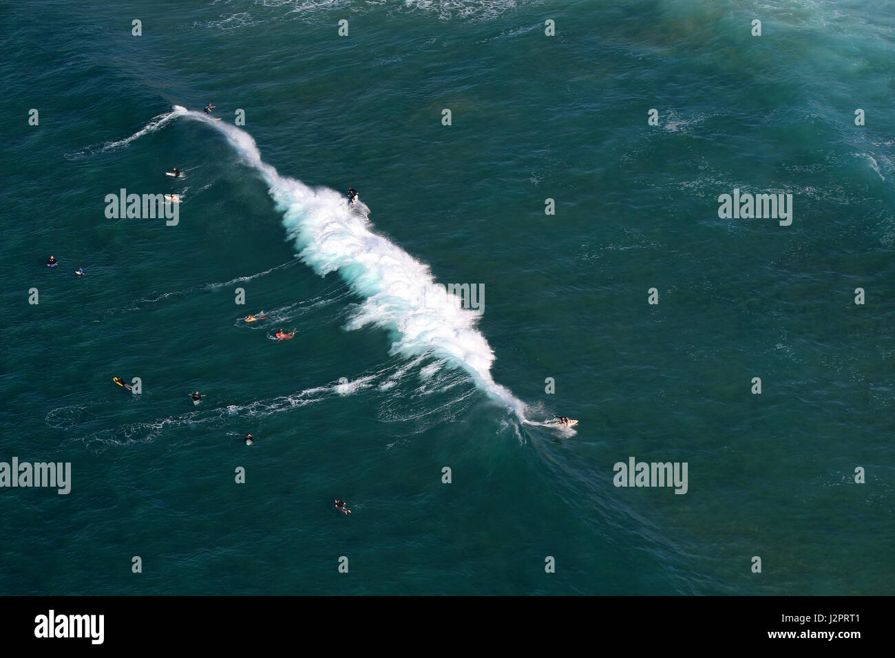 Aerial perspective of surfers riding a wave in the ocean Stock Photo ...