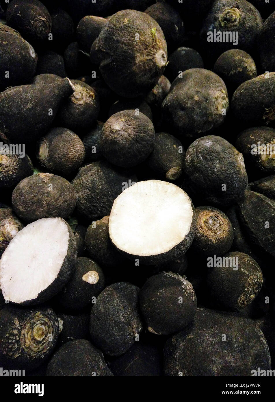 A bunch of whole black turnips and two white halves on the market Stock ...
